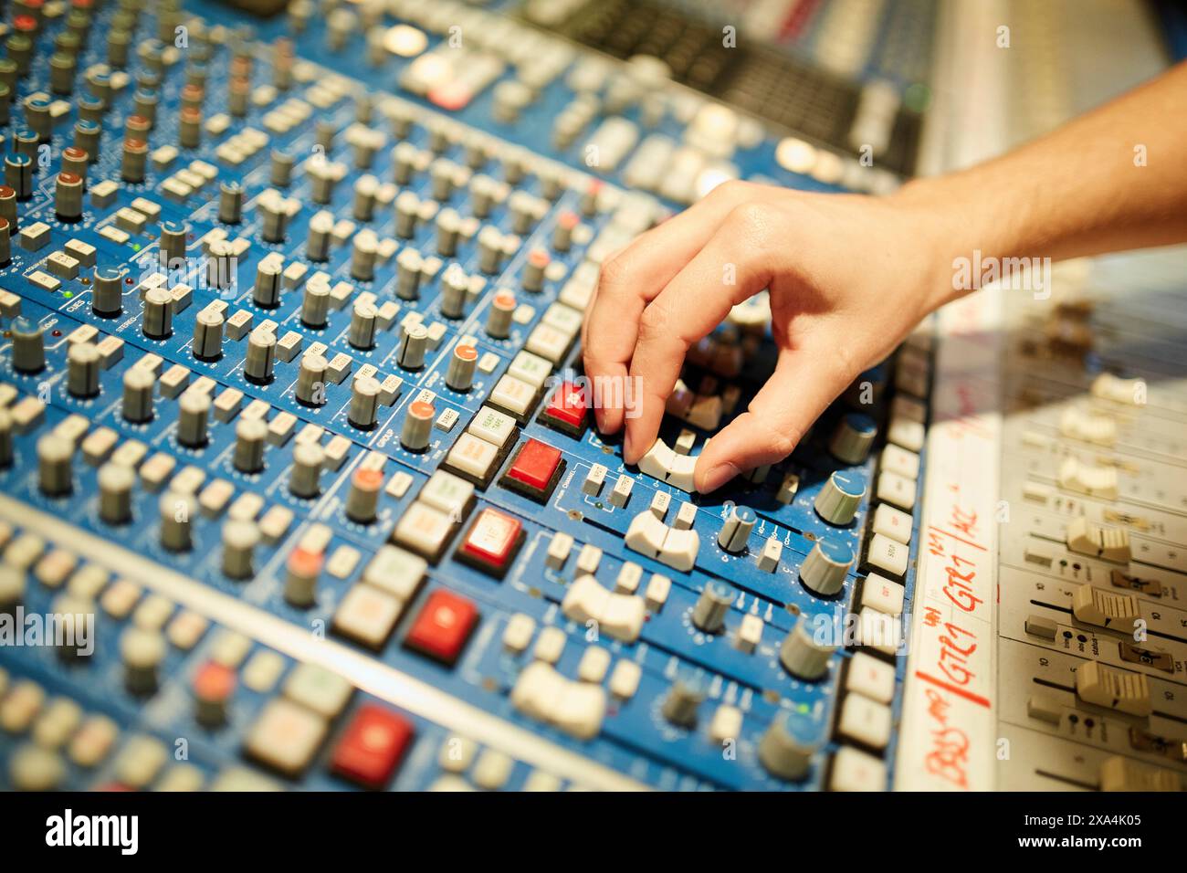 A hand adjusting a knob on a professional audio mixing console with ...