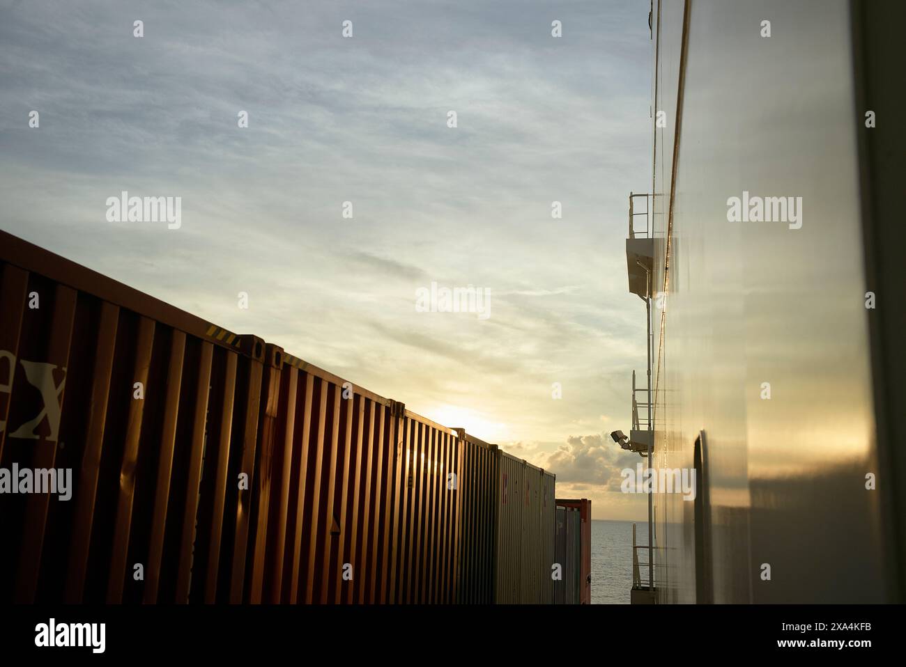 The image captures side cargo ship stacked shipping containers sunset ...