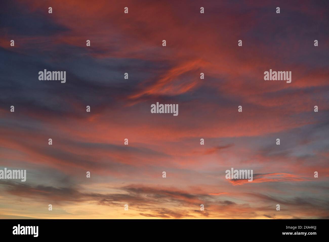 The image captures a vibrant sunset sky with a blend of orange, red ...