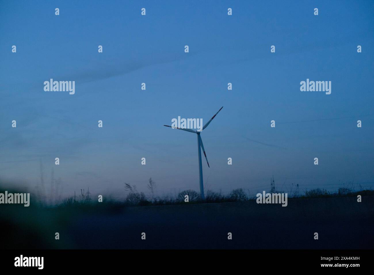 A single wind turbine stands against a twilight sky with a gradient ...