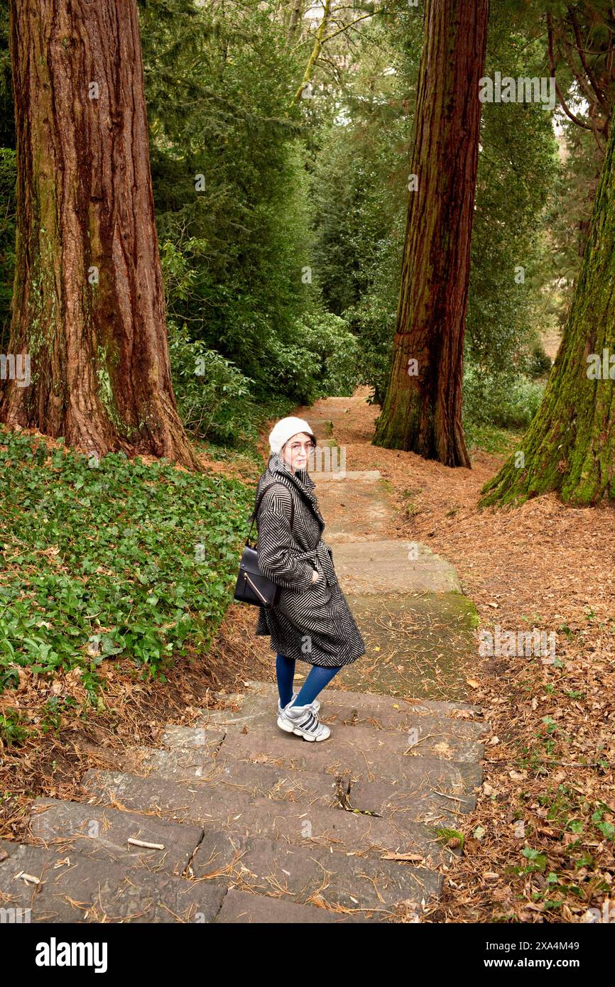 A woman smiles softly while walking down a forest pathway lined with ...