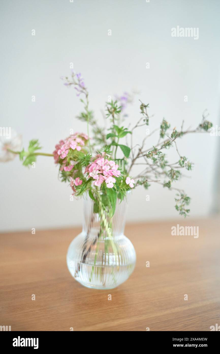 A clear glass vase with a variety of fresh flowers is displayed on a ...