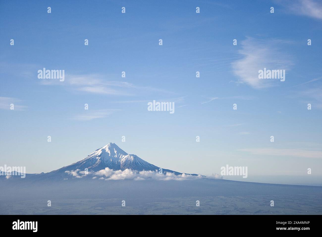 A snow-capped volcano majestically rises above a sea of clouds under a clear blue sky, Mt ...