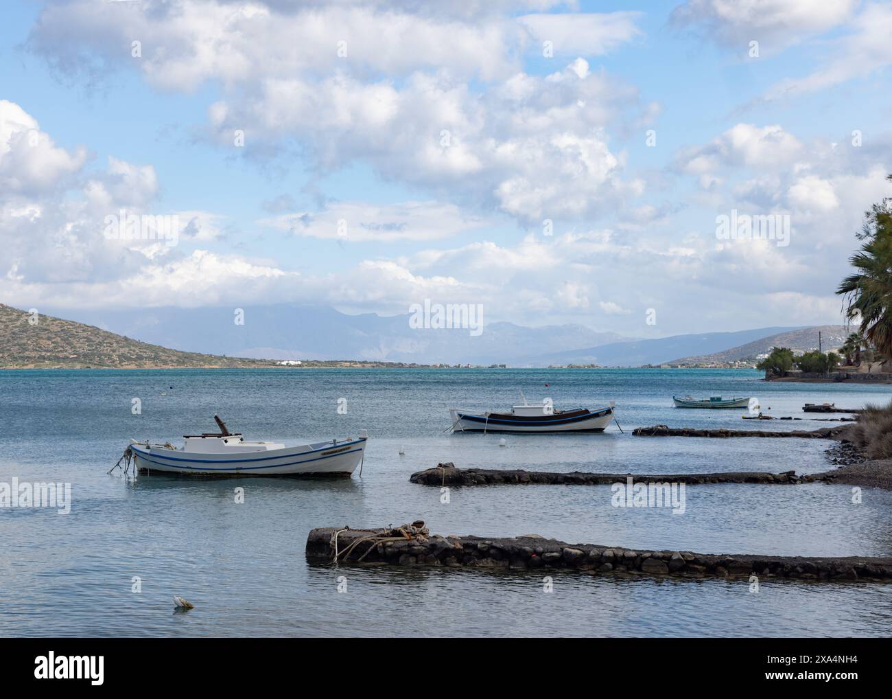 Three local fishing boats moored to jetties along the shorelinw between ...