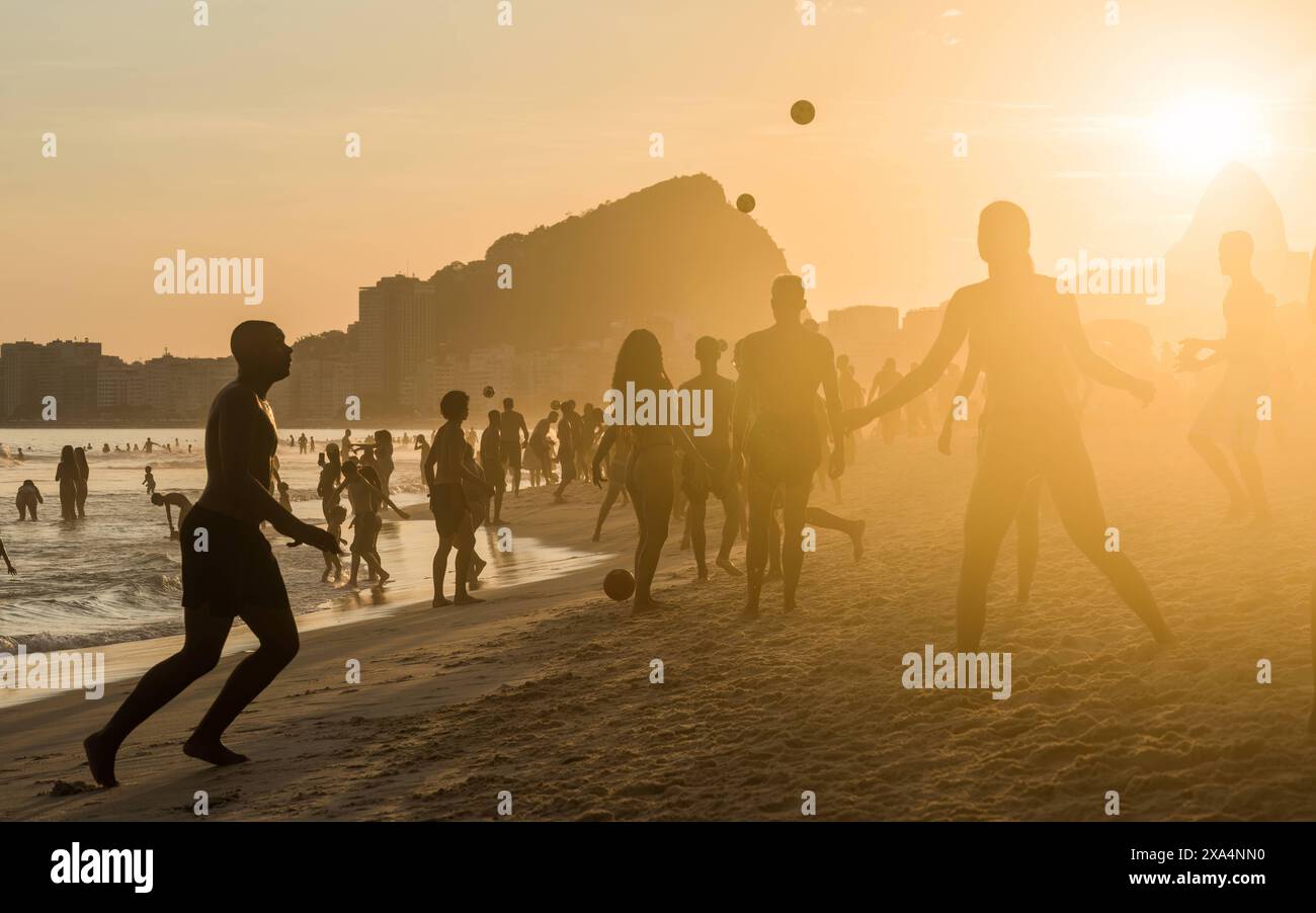 People relaxing and playing keepy-uppy at sunset, Copacabana Beach, Rio ...