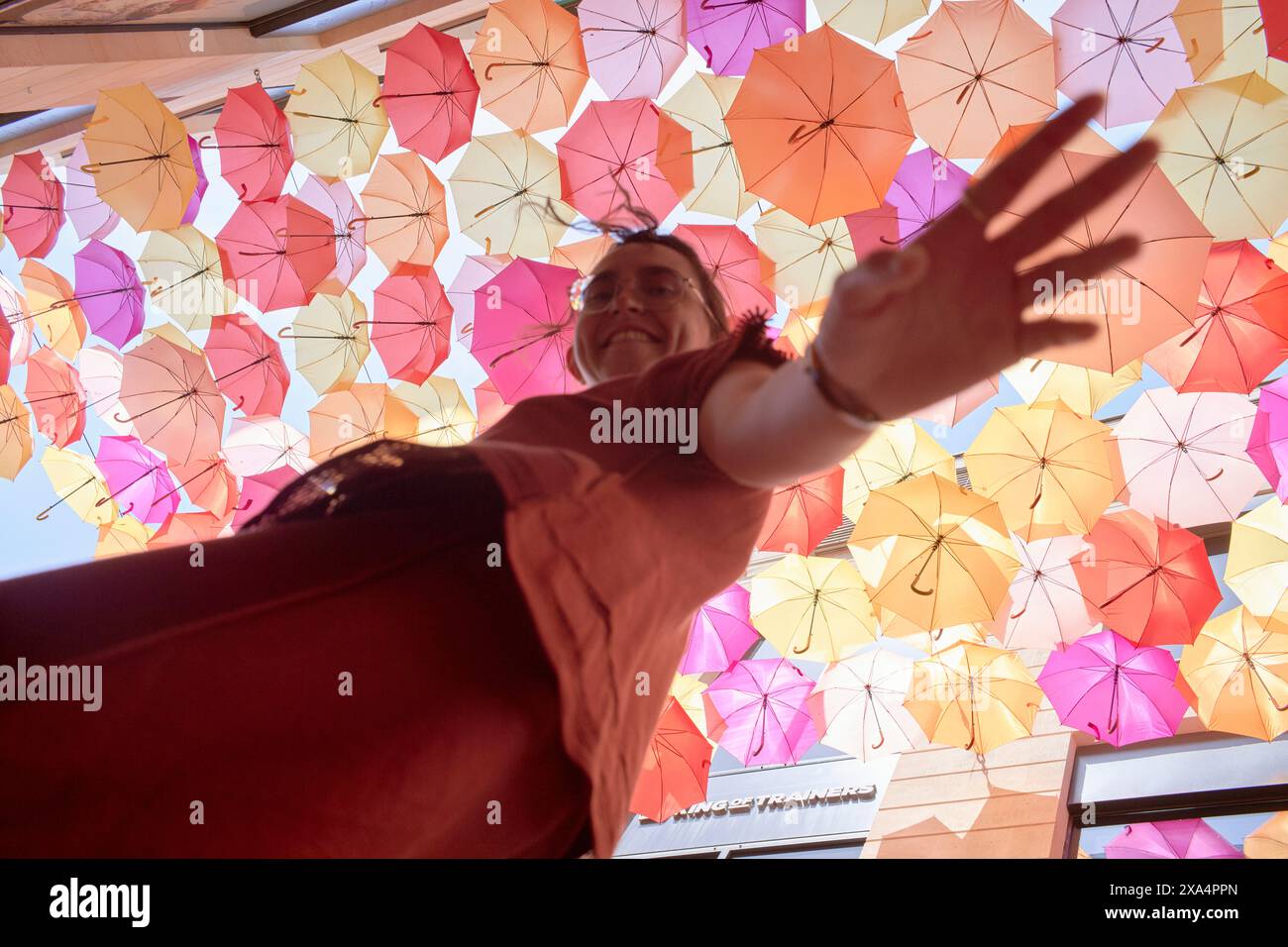 A joyful young woman reaching towards the camera below a vibrant ...