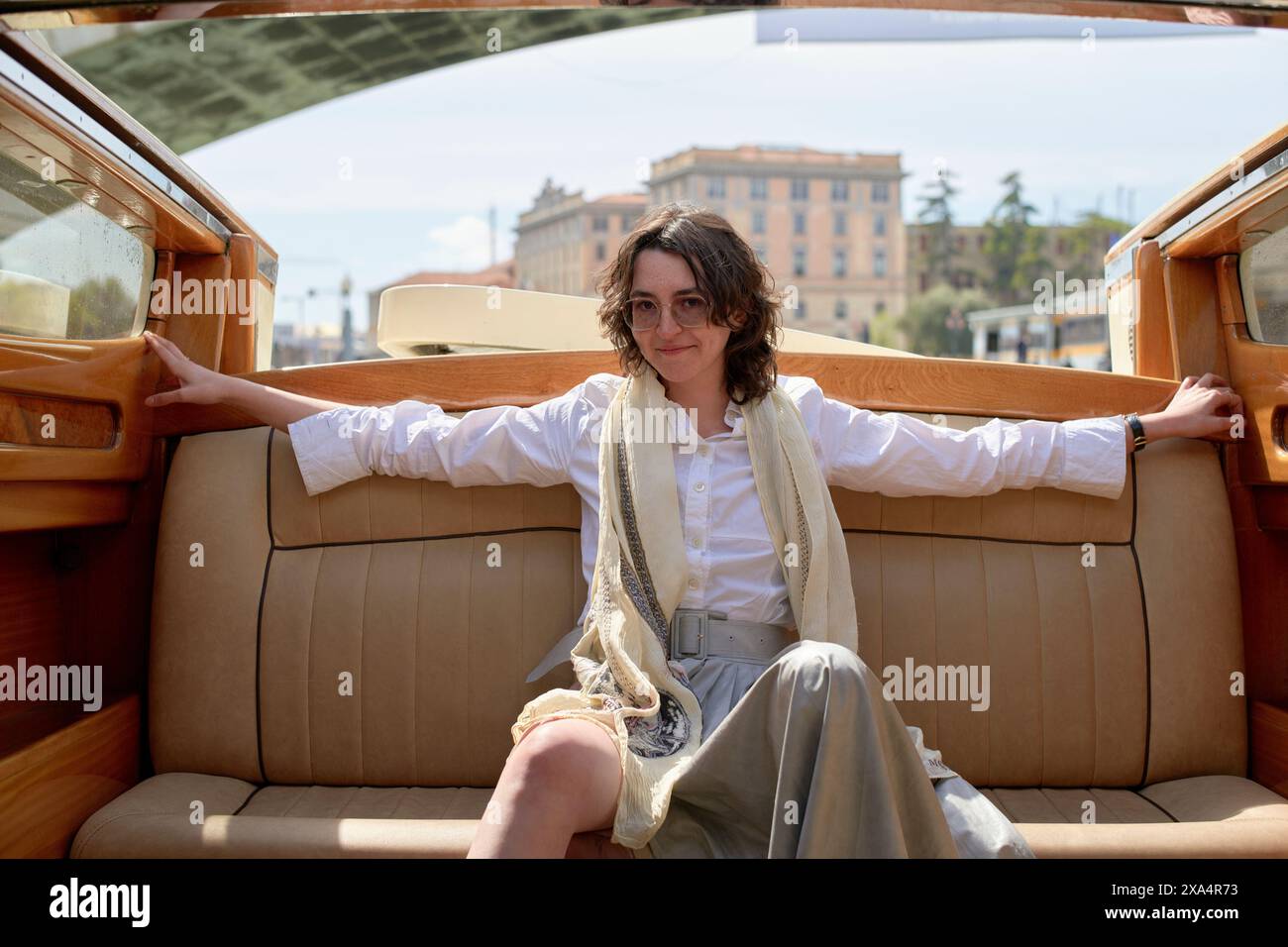 Young woman enjoys a luxurious ride in a classic car with a scenic city ...