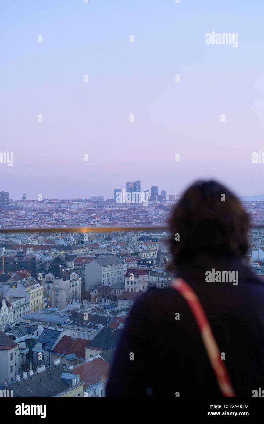 Woman gazing at city skyline during twilight Stock Photo - Alamy