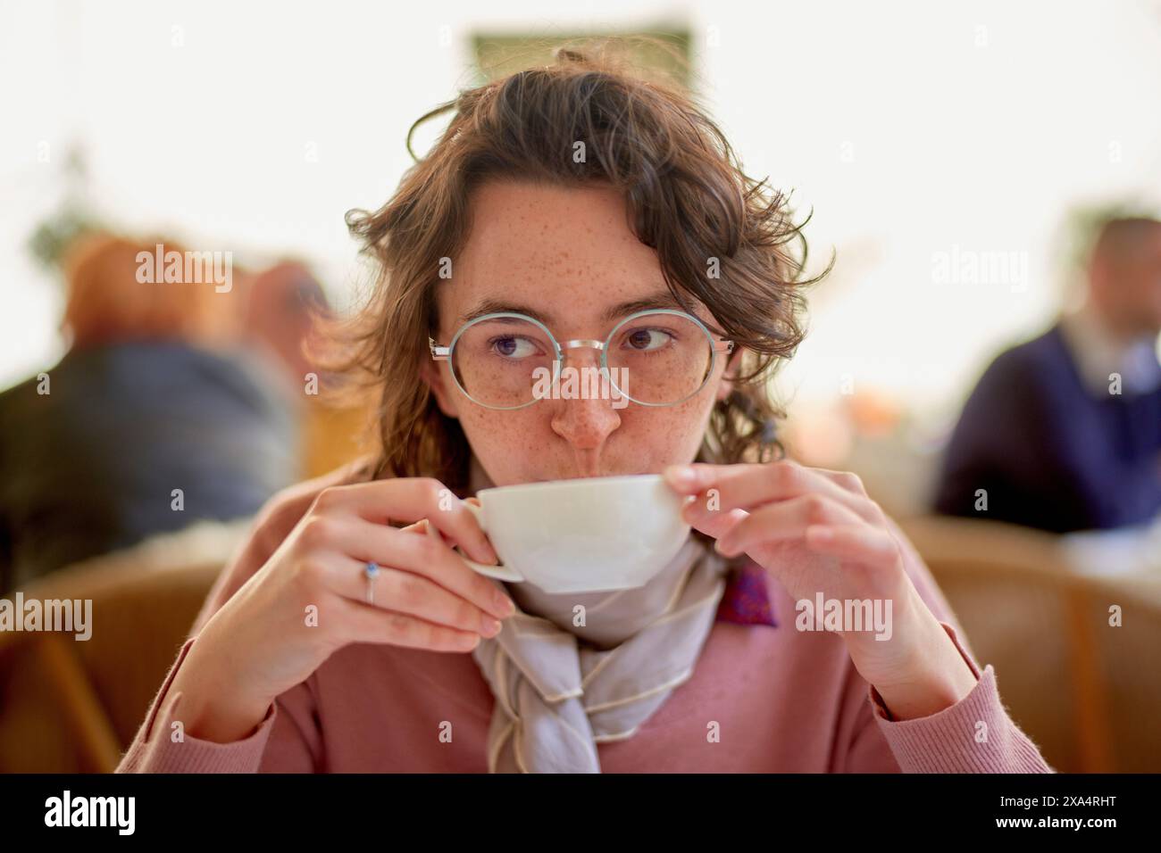 Young woman enjoying a cup of coffee in a cozy cafe setting Stock Photo ...