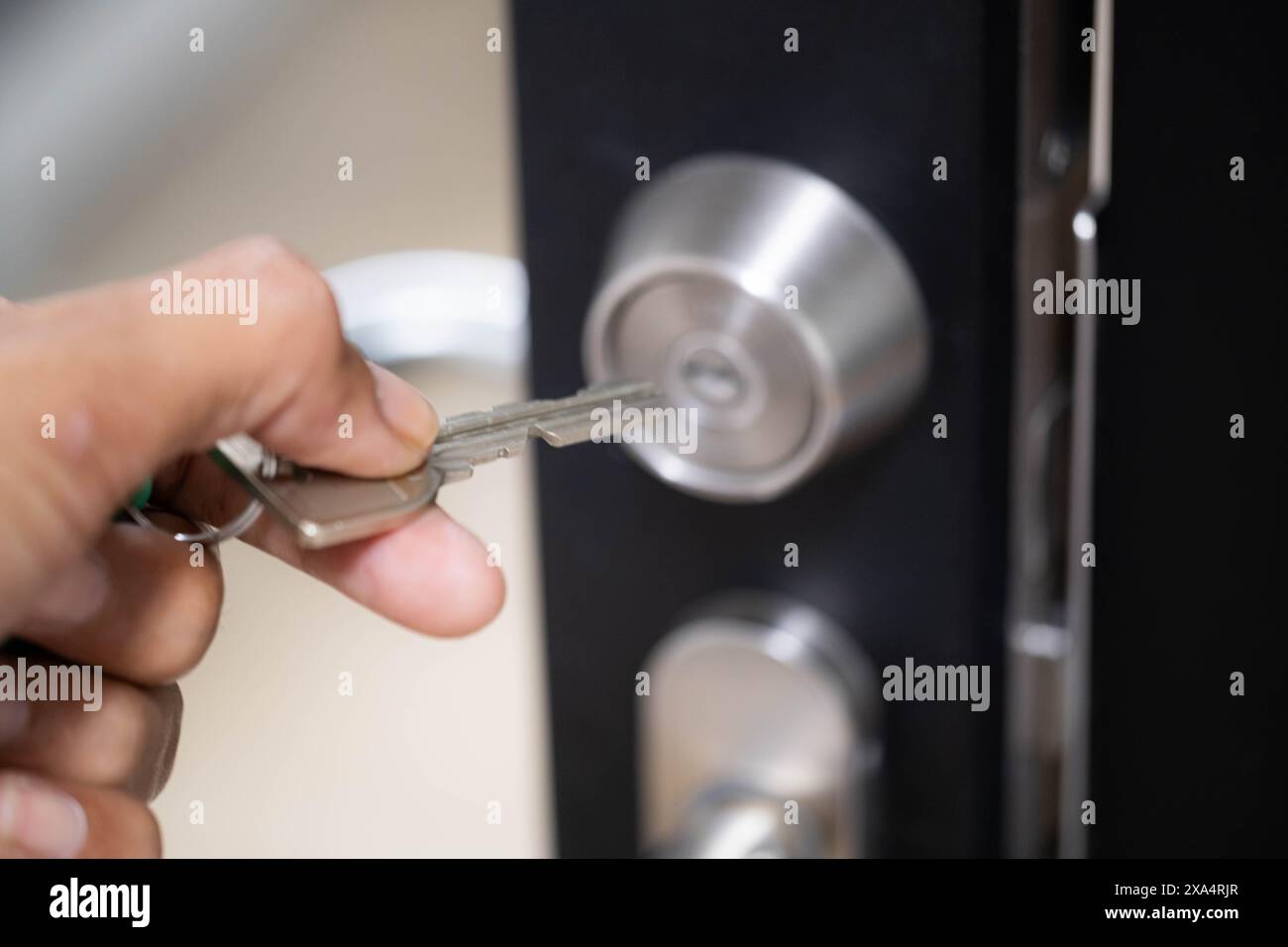 Close-up of a hand inserting a key into a door lock Stock Photo - Alamy