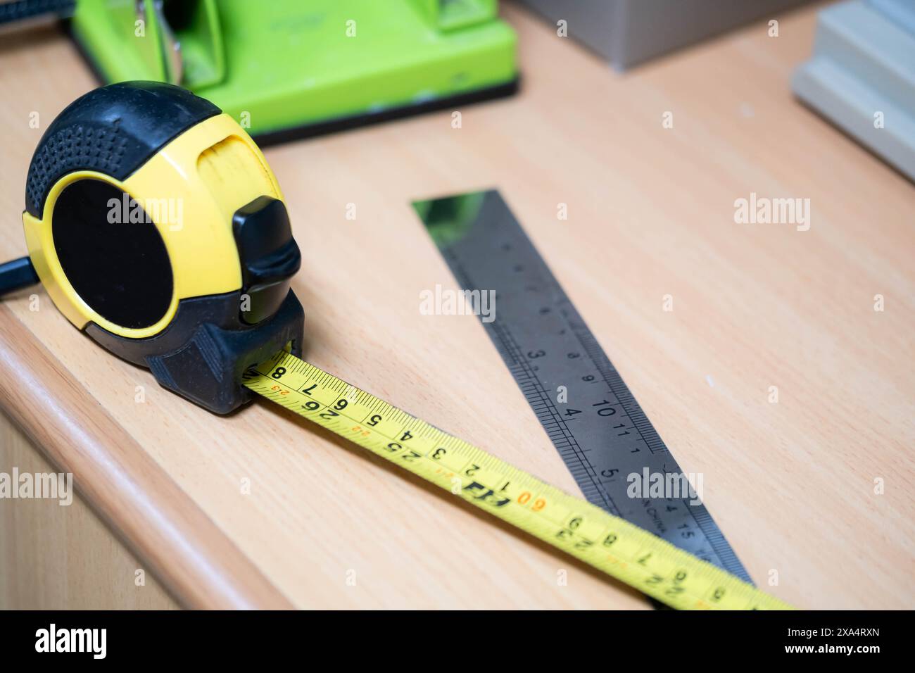 A close-up of a yellow and black tape measure extended on a wooden desk ...