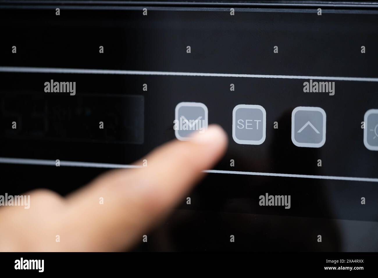 Close-up of a person's finger pressing the down button on a digital ...