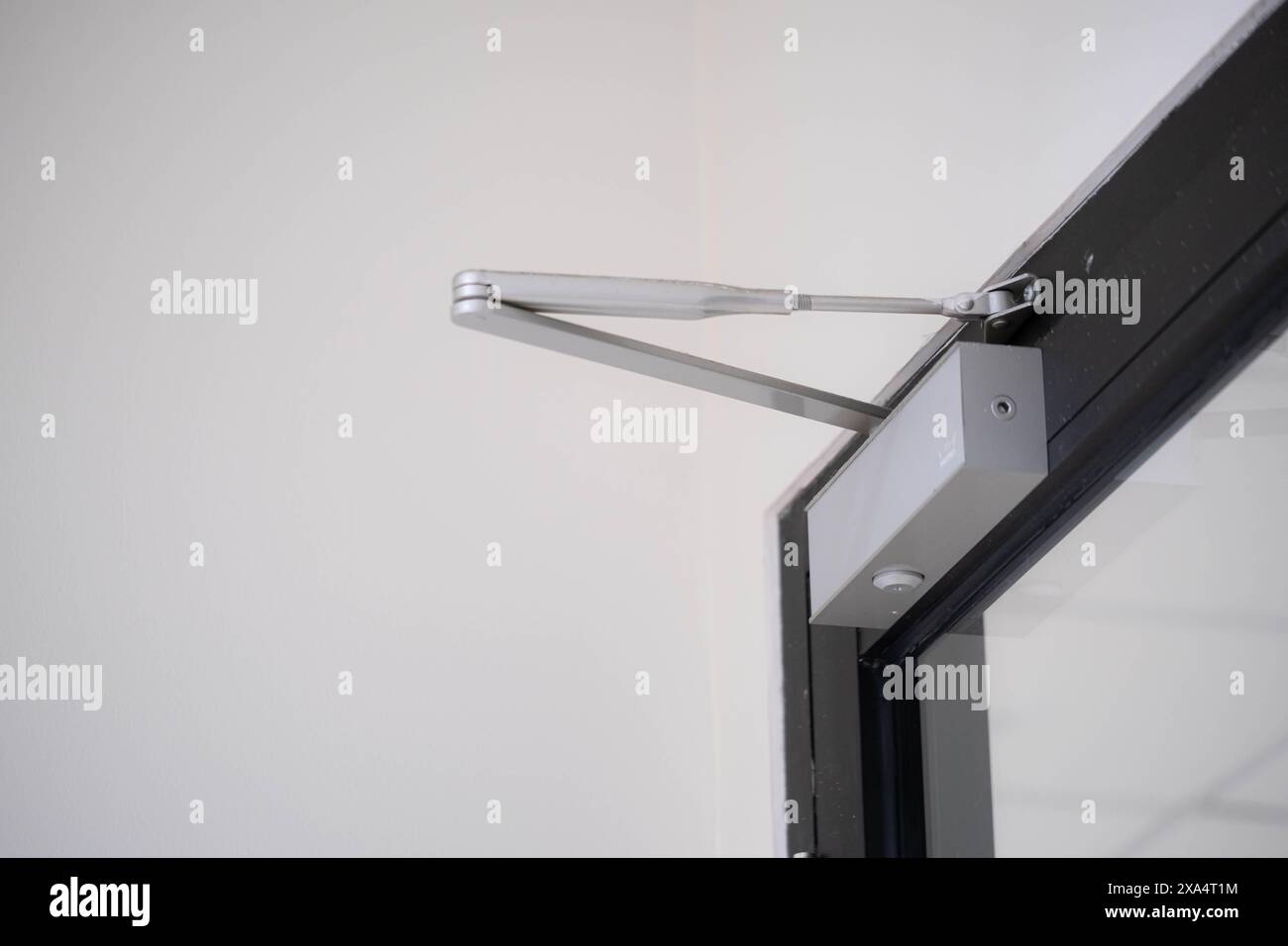 Close-up of a door closer mechanism installed on a glass door in an ...