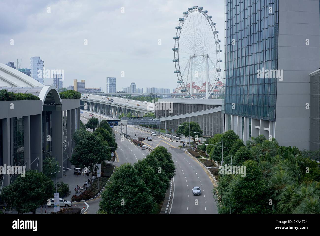 Urban landscape with a giant Ferris wheel overlooking a bustling city street and modern ...
