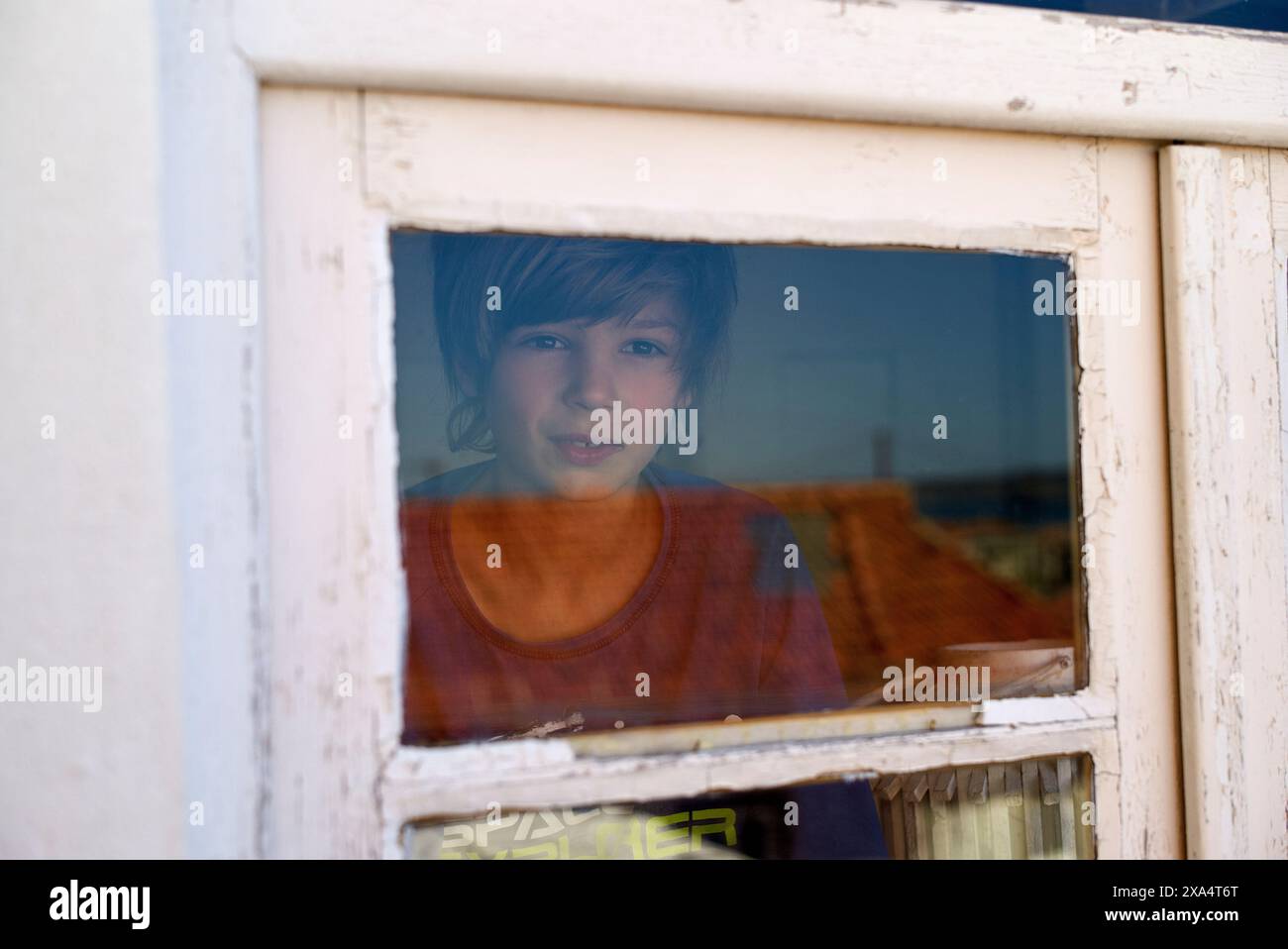Young boy gazing through a vintage white window frame with a serene ...