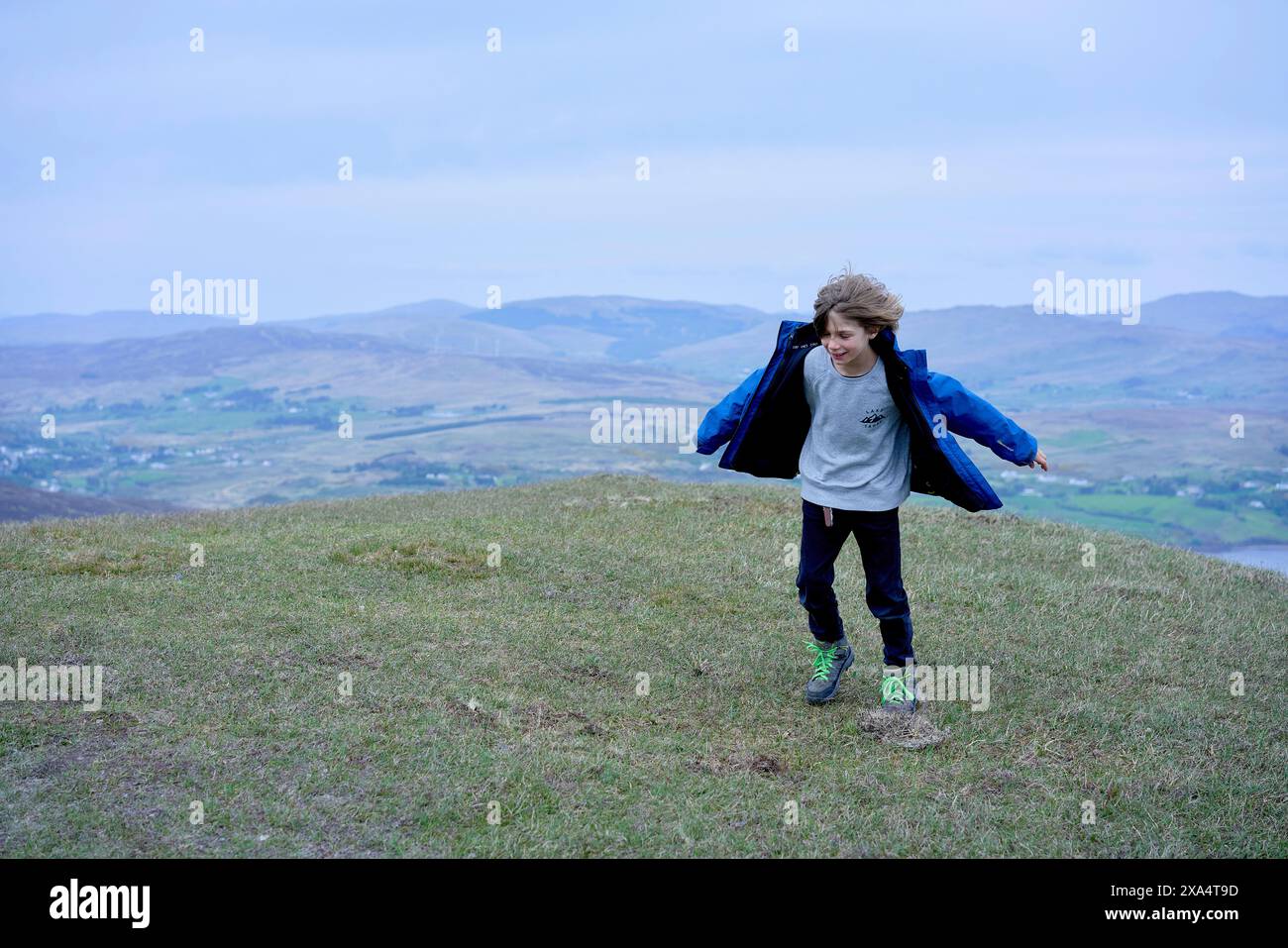 Young child adventuring atop a hill with a picturesque valley backdrop ...