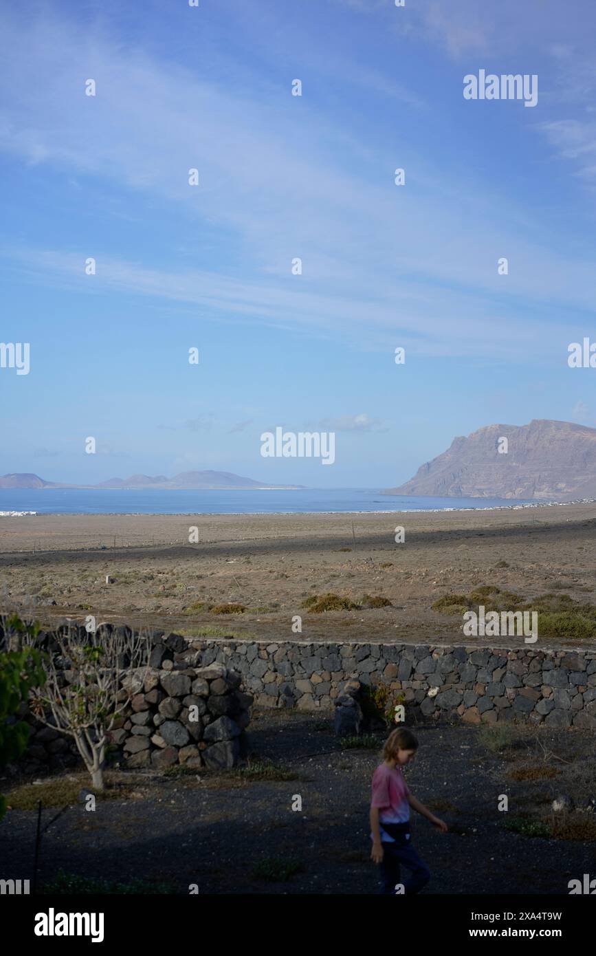 A child walks by a stone wall on a path with a scenic view of a ...