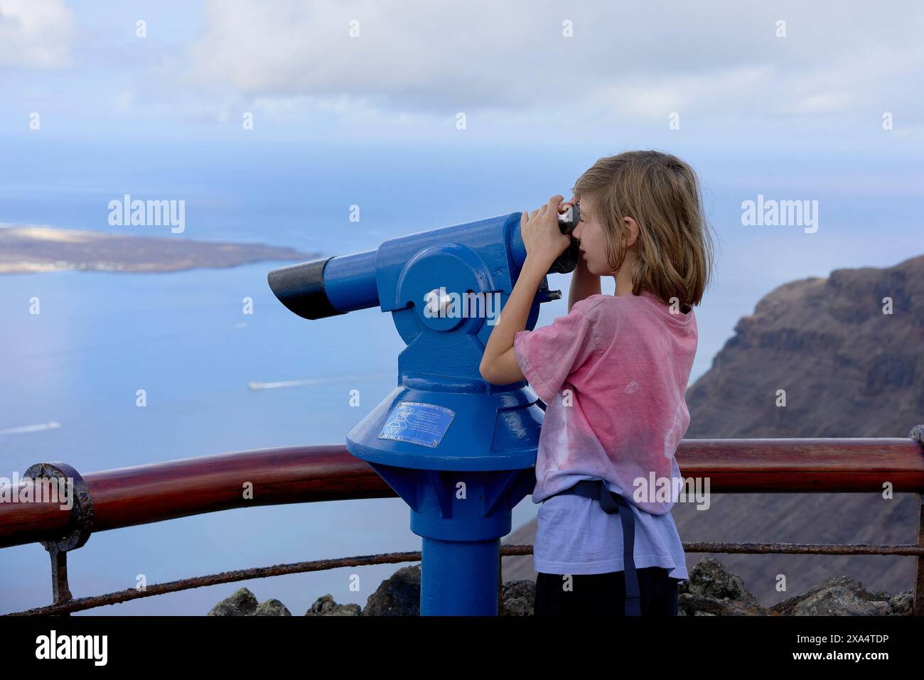 Child using a coin-operated telescope at a scenic viewpoint overlooking ...