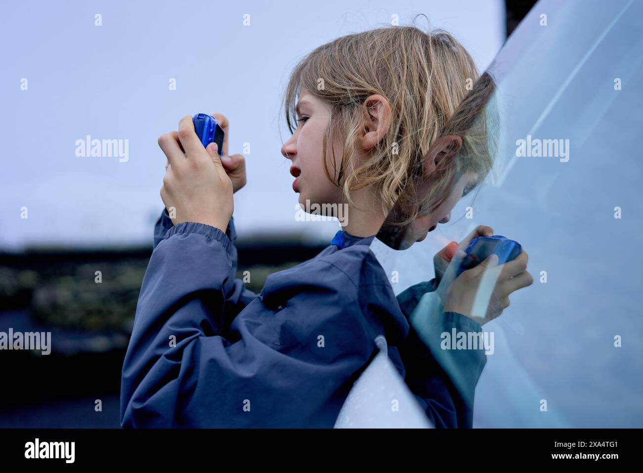 Young child taking a photo with a blue camera, reflection visible on a ...
