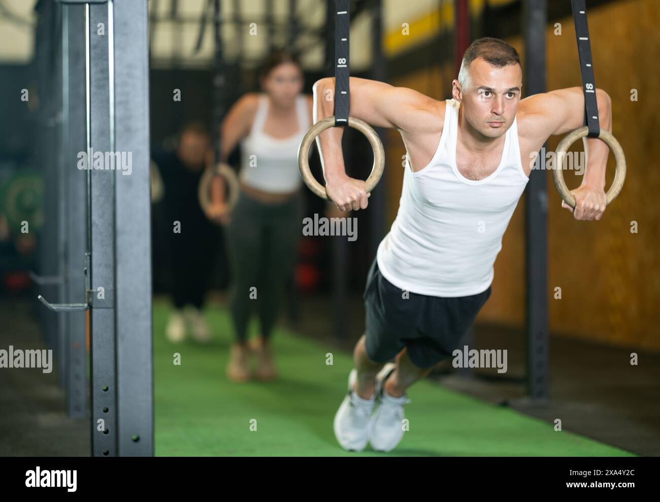 Man performing chest push-ups with gymnastic rings during workout in gym Stock Photo - Alamy