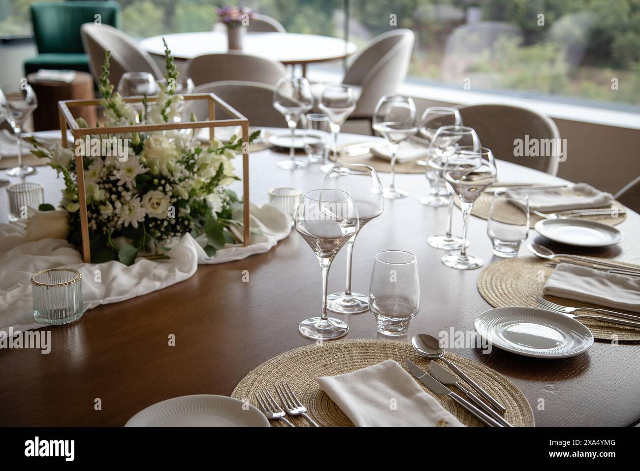 Elegant dining table set for a special event, featuring a beautiful floral centerpiece, wine ...