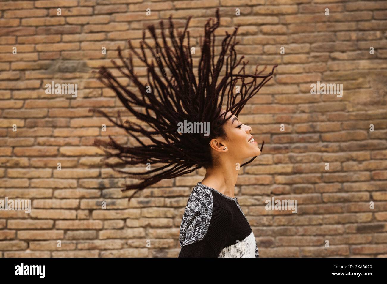 Woman moving her dreadlocks swirling dynamically around her as she ...