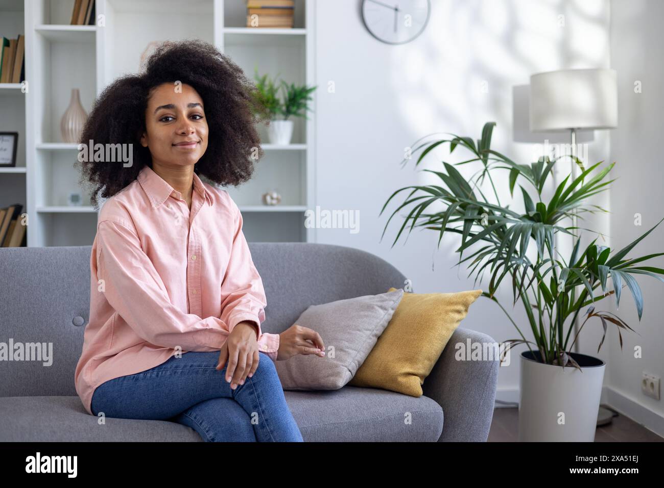 Young woman sitting comfortably on a sofa in a modern living room with ...