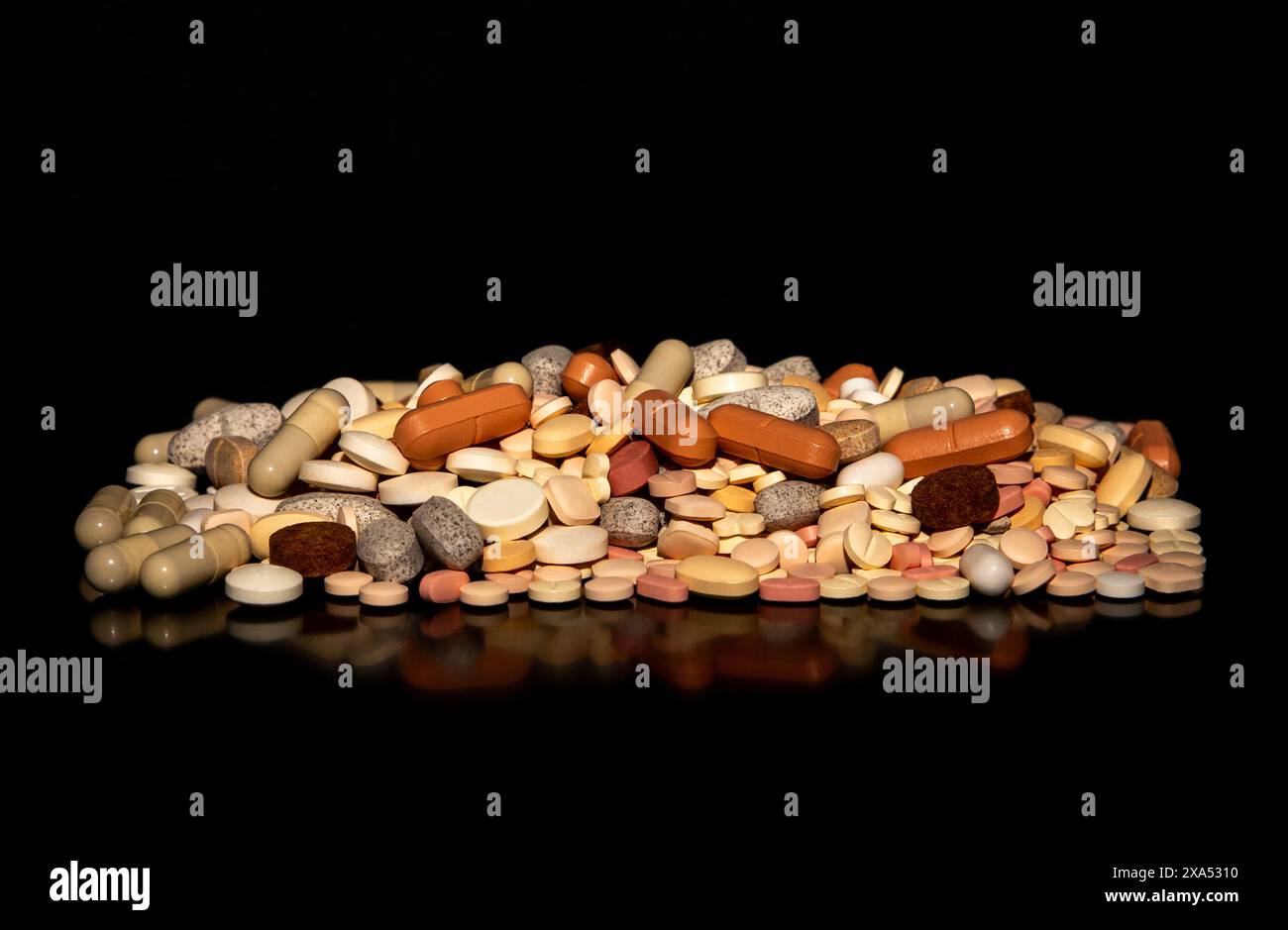 A Close-up with a pile of different medicine tablets on a black ...