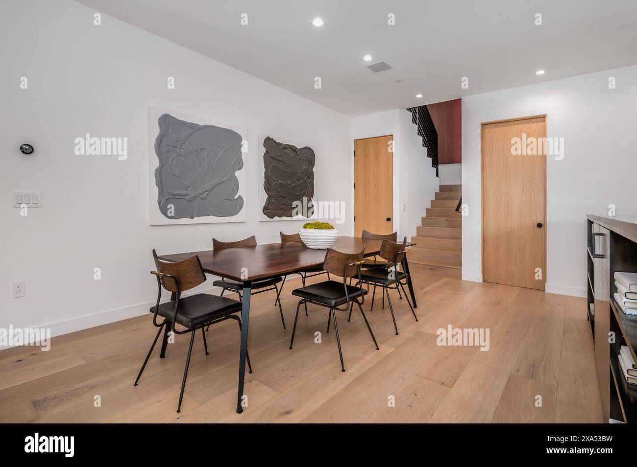 A corner dining area with table, chairs, kitchen, and staircase nearby ...