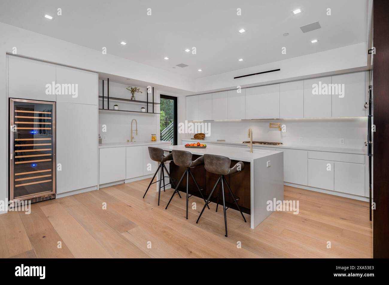 White kitchen with stools at a counter and fridge Stock Photo - Alamy
