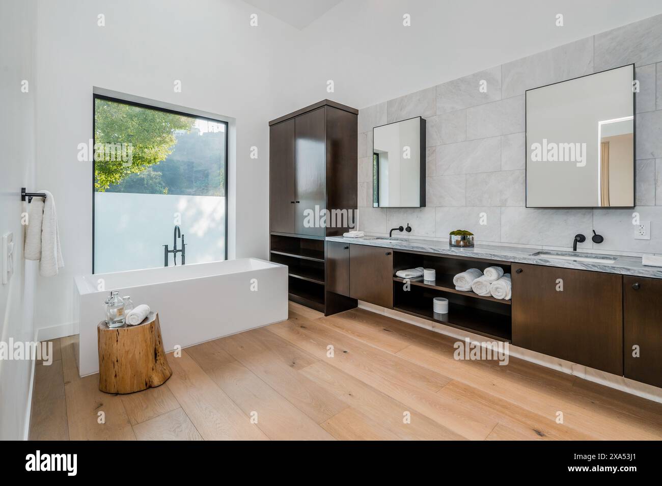 Spacious bathroom with oversized mirrors, wooden cabinets, and sinks ...