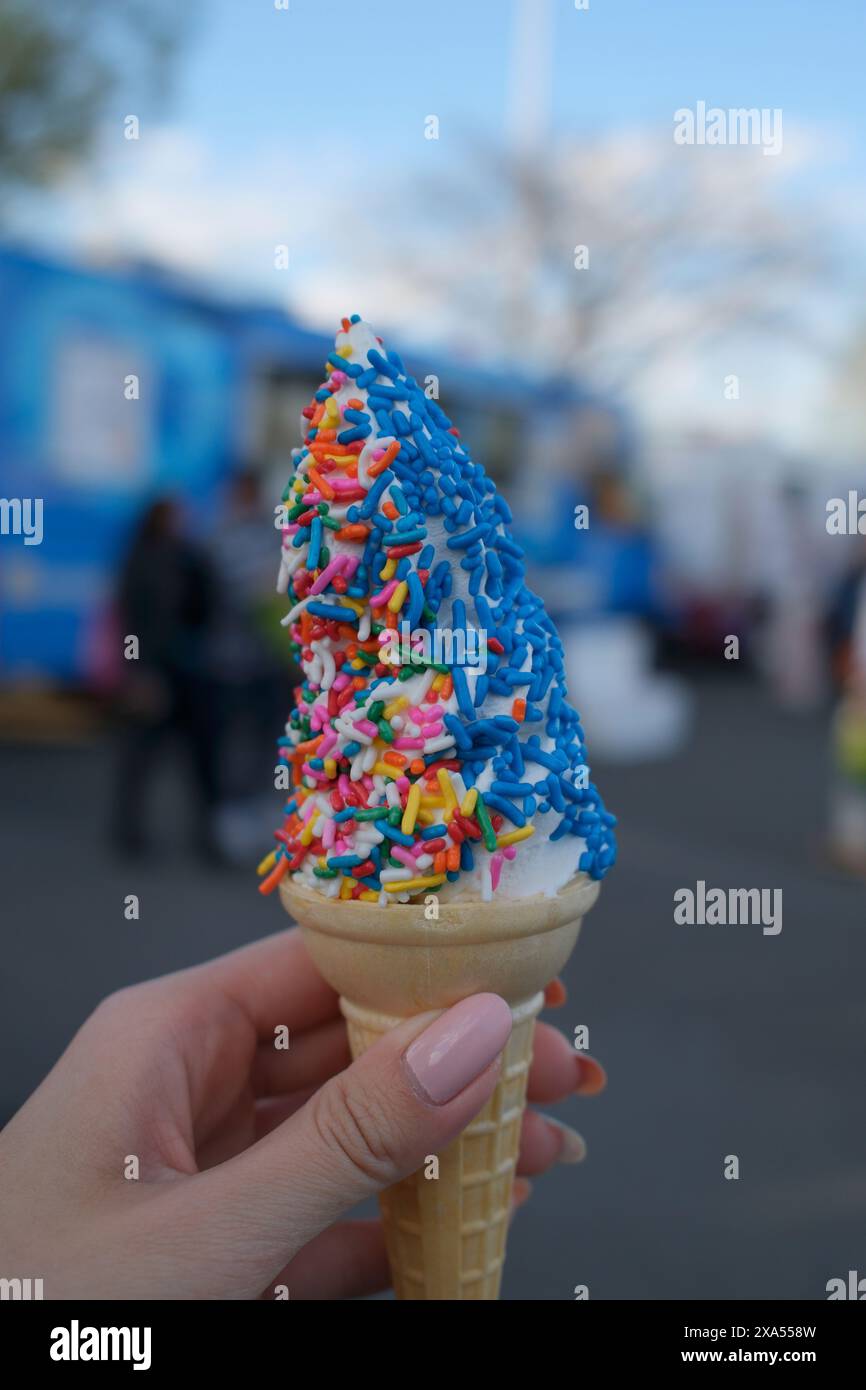 An kice cream cone topped with colorful sprinkles and a chocolate candy ...