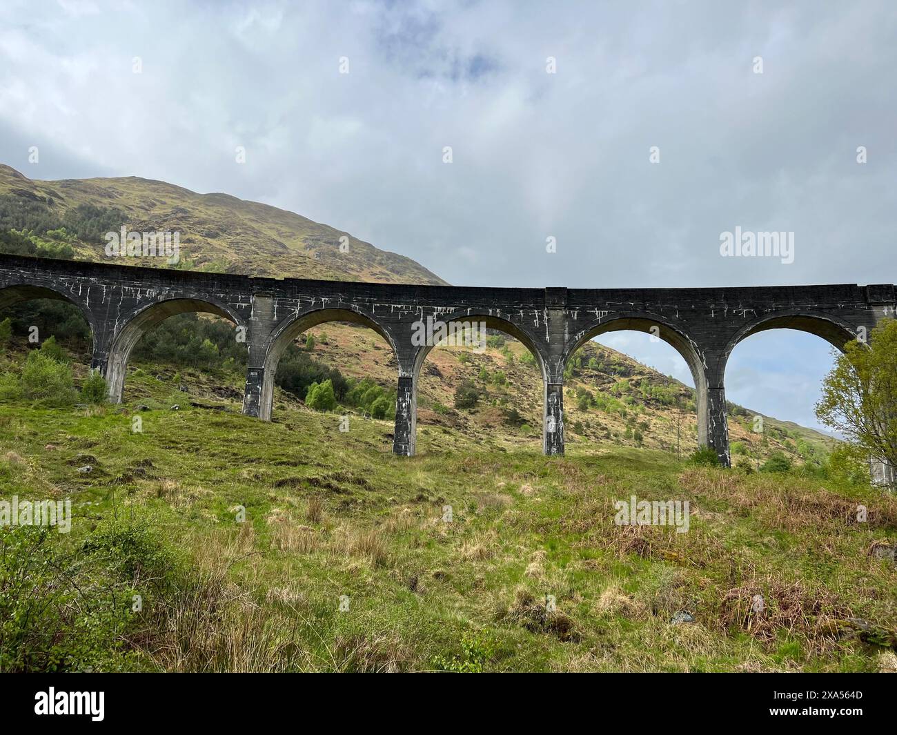 Arched bridge on grassy hill with distant mountains in Scotland Stock ...