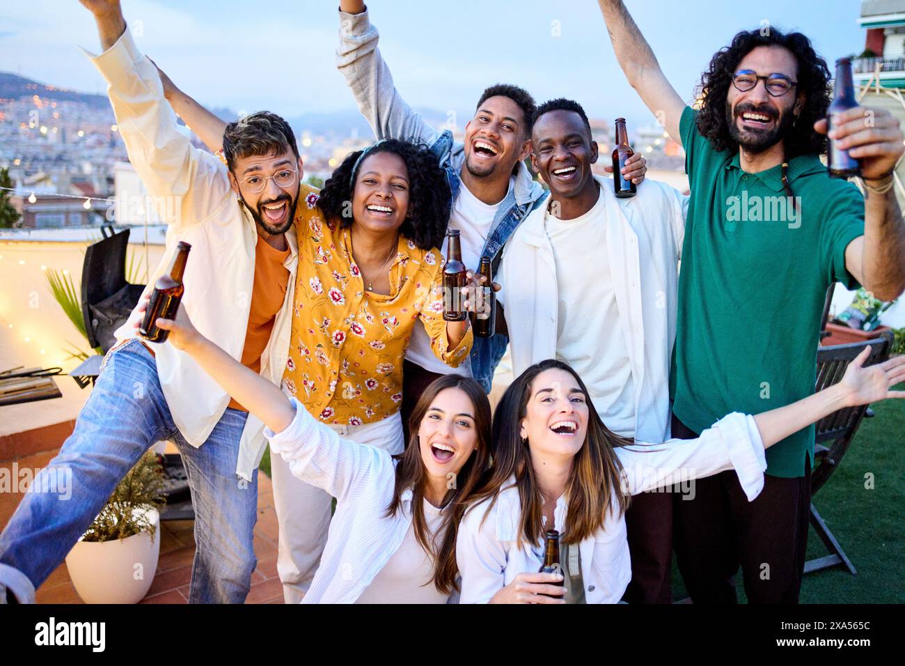 Group of diverse excited friends celebrating with beers at barbecue ...