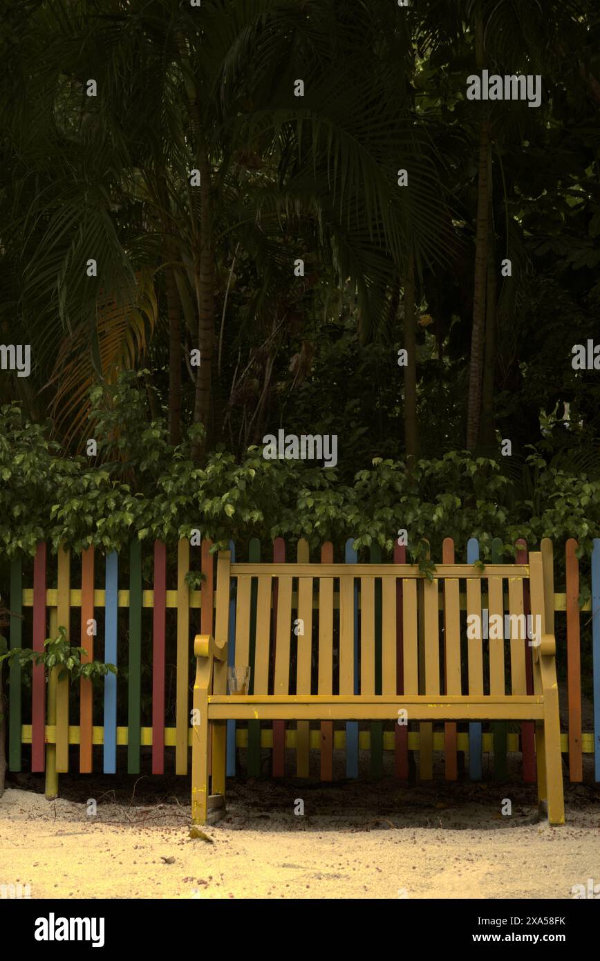 Colorful park bench behind a fence in yellow and multiple hues Stock ...