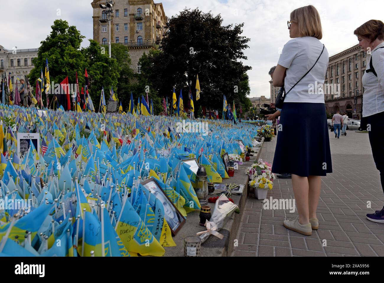 People looking at a huge memorial display of Ukrainian flags carrying ...