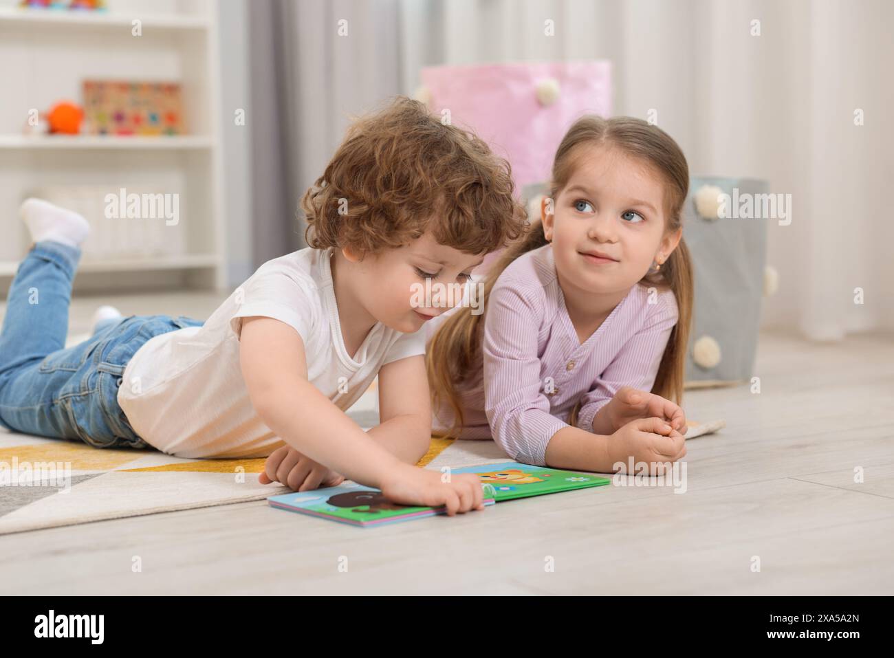 Cute little children reading book on floor in kindergarten Stock Photo ...