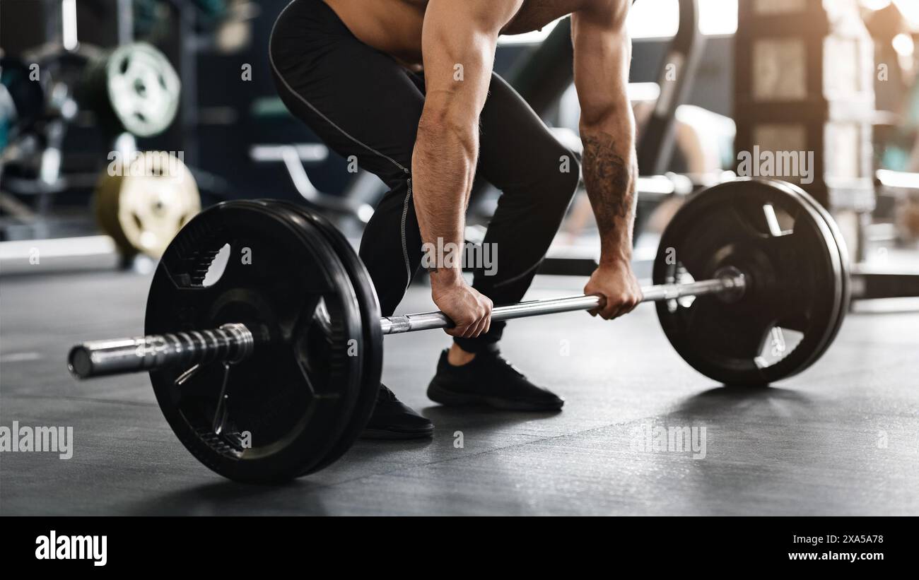 Muscular powerlifter lifting heavy barbell from gym floor Stock Photo ...