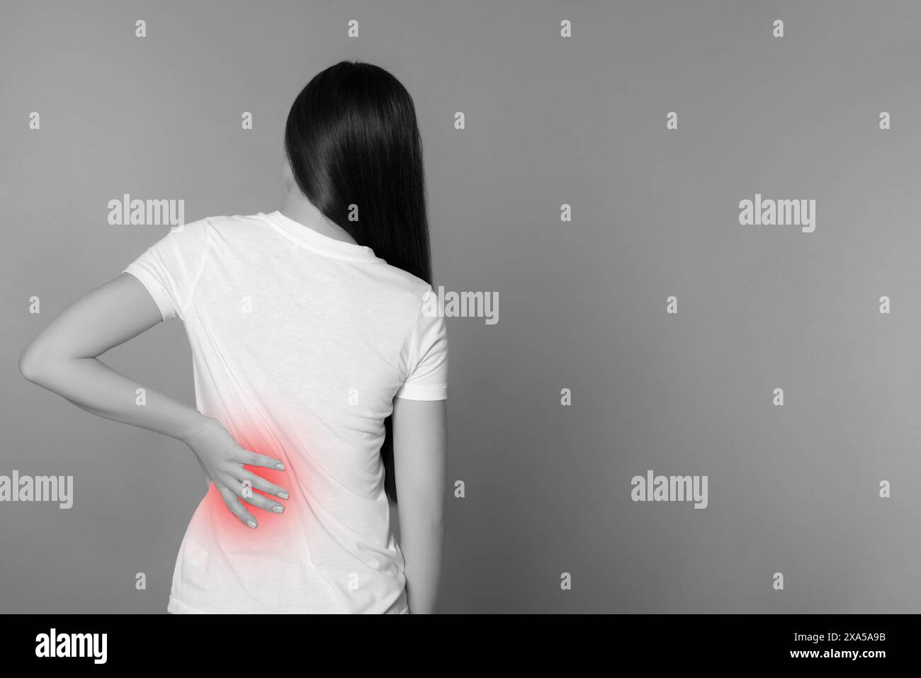 Woman suffering from back pain on grey background. Black and white ...