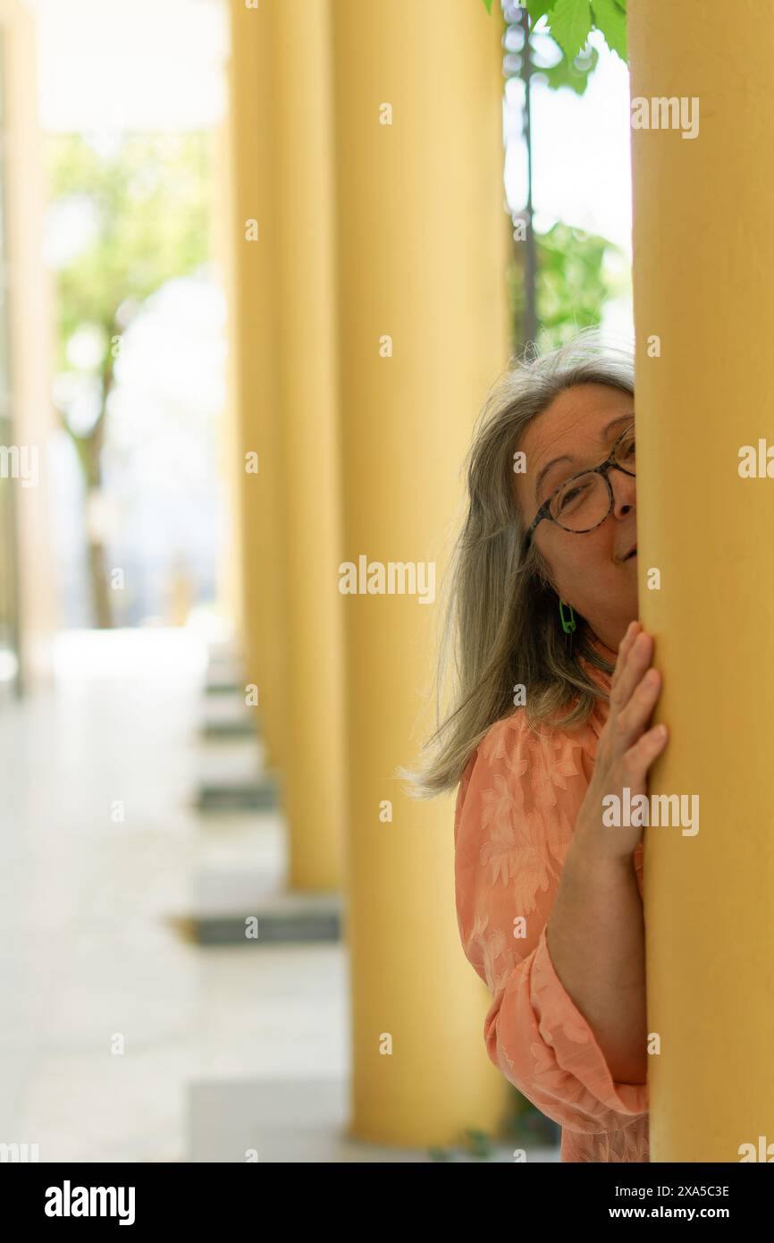 An older woman with white hair and glasses, smiling from behind a ...
