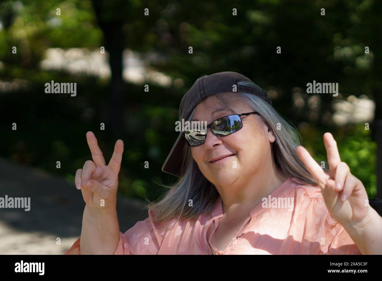 A cheerful and funny older gray-haired woman with cap and sunglasses ...