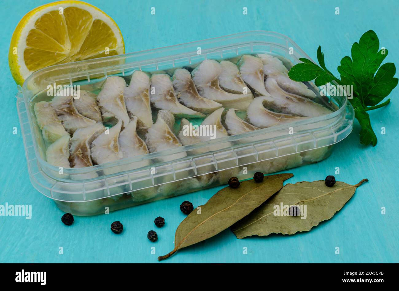 Marinated fish in a plastic container. Pieces of pickled herring in an ...