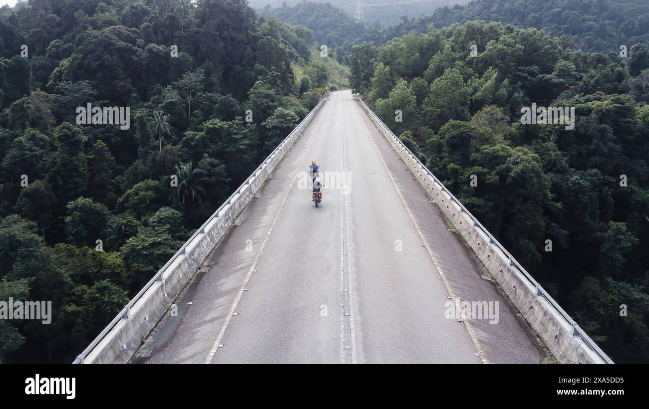 Aerial view of motorcycles on the elevated road across the rainforest ...