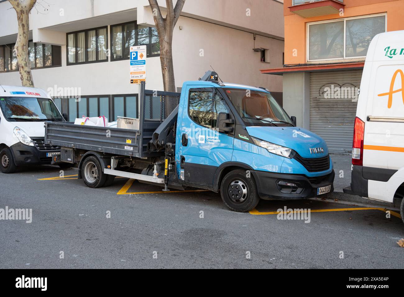Blue Iveco Daily truck with crane arm parked on the street. Pipeline ...