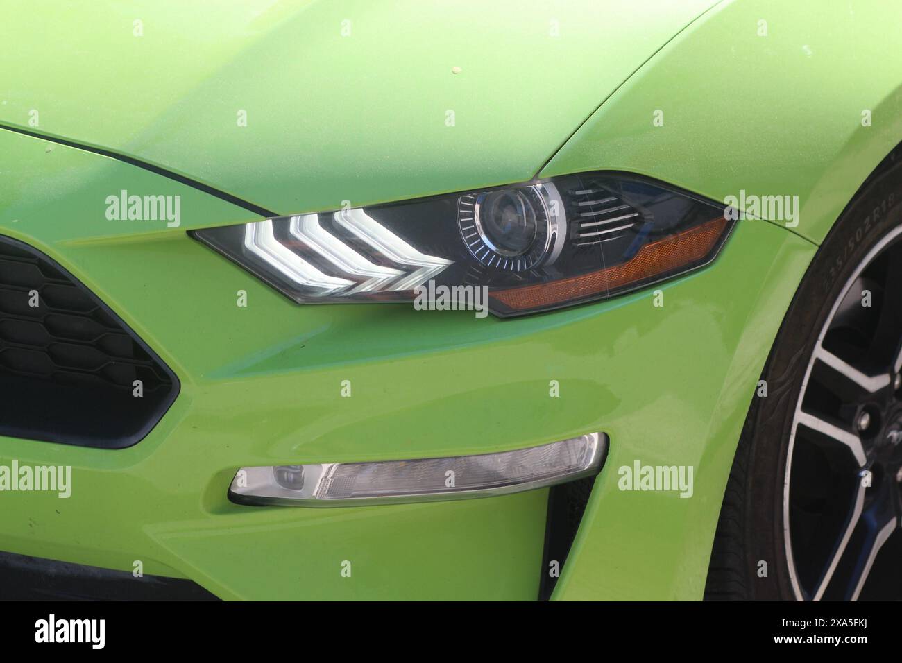 A close-up shot of green modern car's headlights and front bumper Stock ...