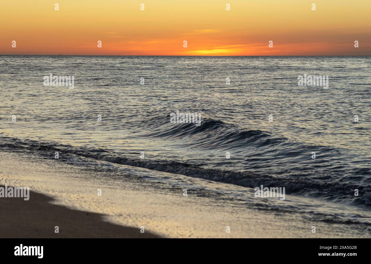 An incredible sunrise unfolds over the beach, stretching to an infinite ...