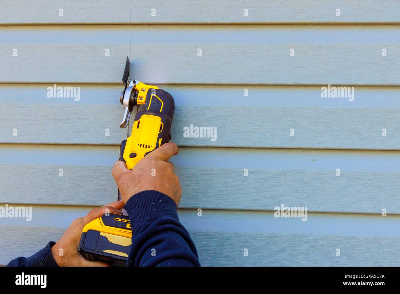 Damaged vinyl siding is removed using multi tool during reconstruction ...