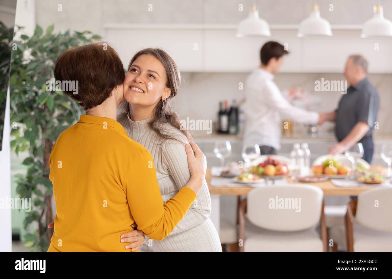 Happy adult daughter warmly welcoming with hug and kiss senior mother ...