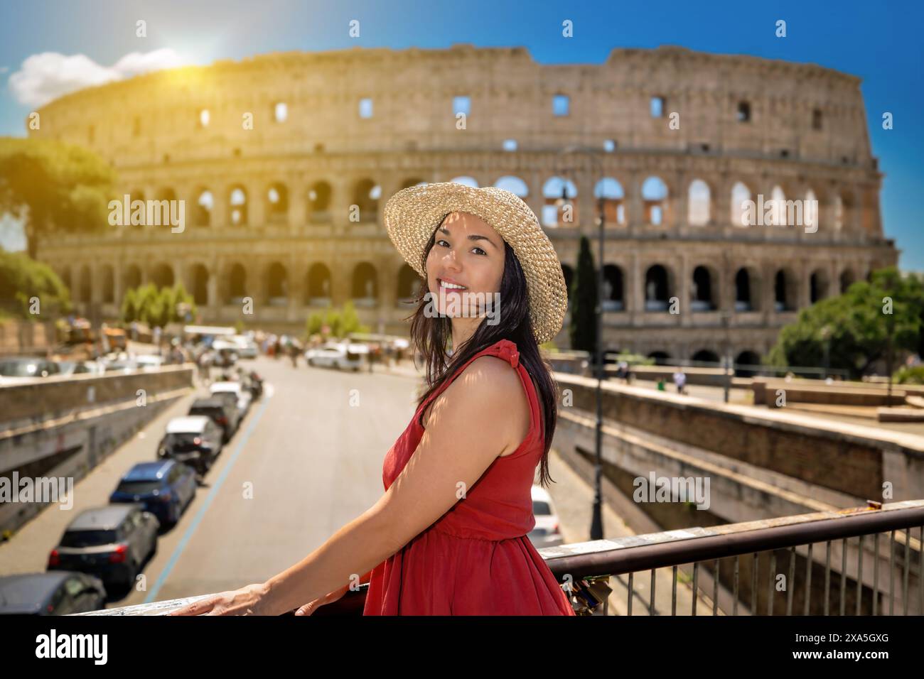 Brunette girl in a straw hat and a red dress admires the ancient ...