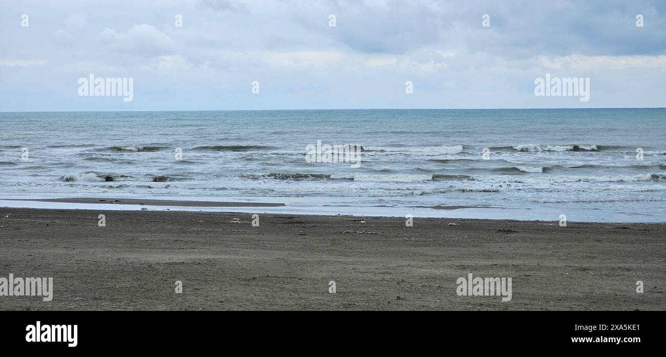 A beach with a bench facing the ocean and waves Stock Photo - Alamy